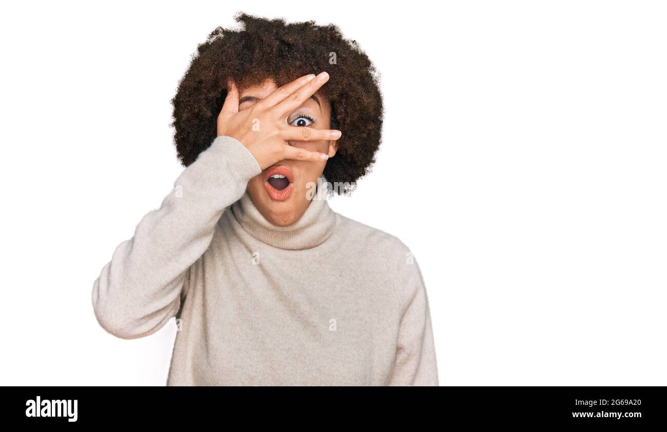 Young hispanic girl wearing wool winter sweater peeking in shock ...