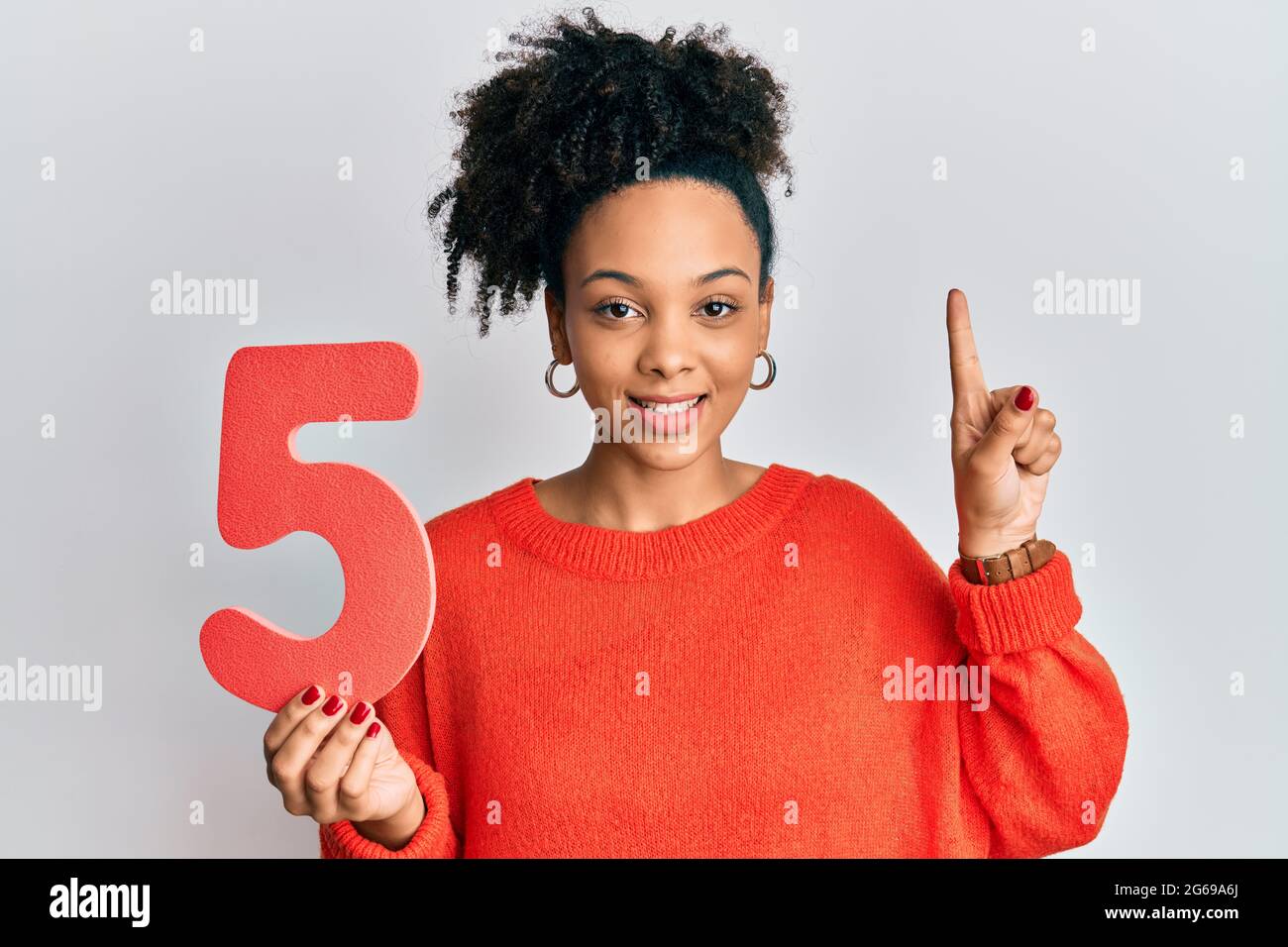 Young african american girl holding number five smiling with an idea or ...