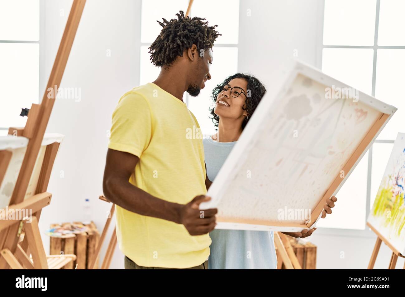 African american artist couple smiling happy holding canvas at art ...