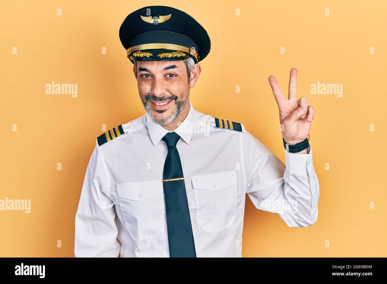 Handsome middle age man with grey hair wearing airplane pilot uniform ...