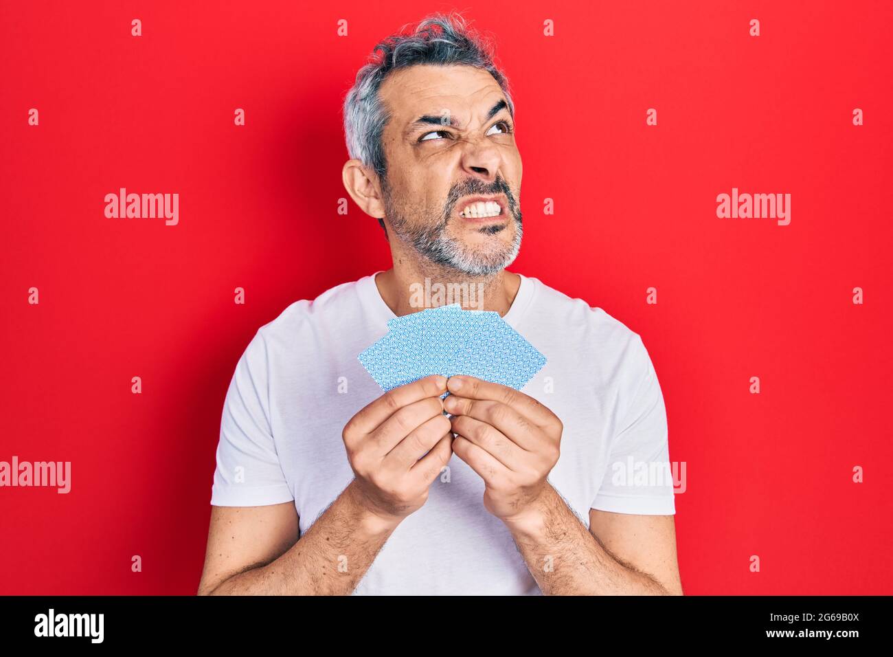 Handsome middle age man with grey hair covering face with cards angry ...