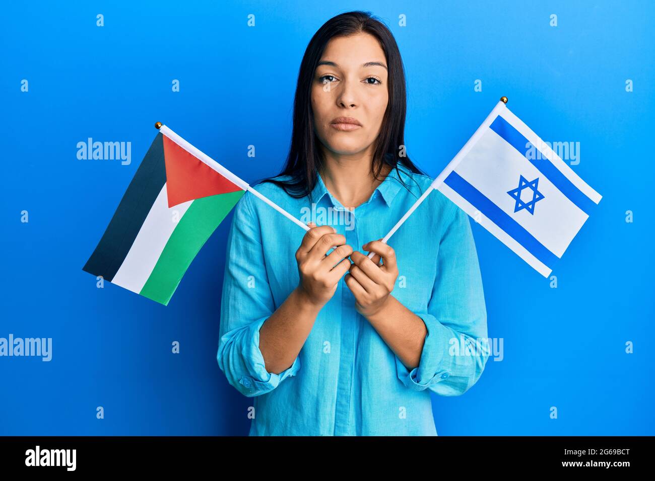 Young latin woman holding palestine and israel flags relaxed with ...
