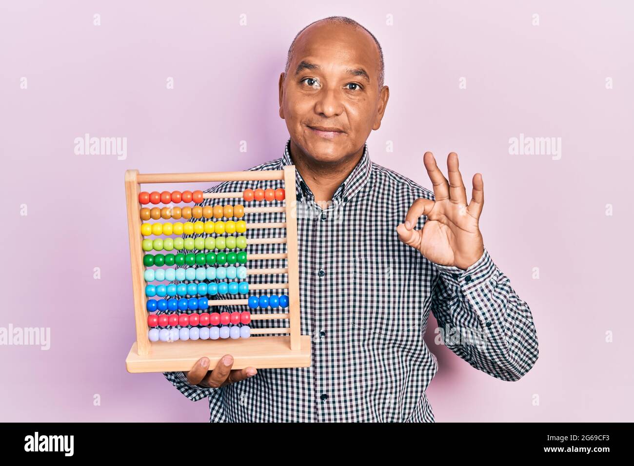 Middle age latin man holding traditional abacus doing ok sign with ...