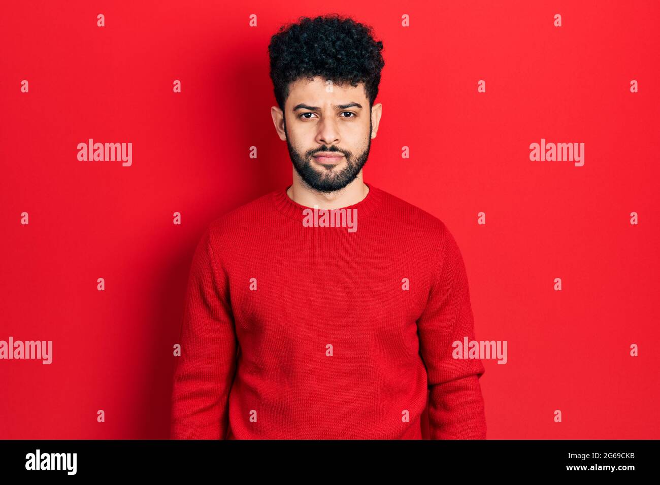 Young arab man with beard wearing casual red sweater depressed and ...