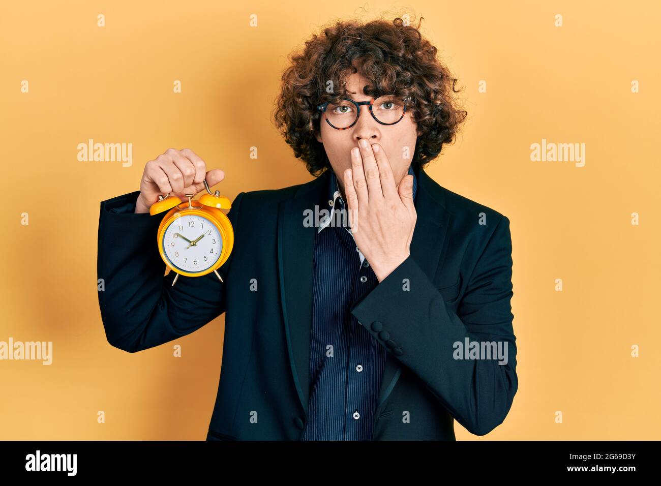 Handsome young man wearing business jacket and holding clock covering ...