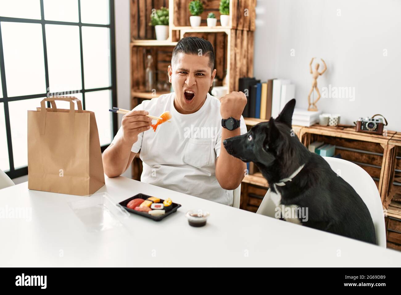 Young hispanic man eating sushi using chopsticks annoyed and frustrated ...