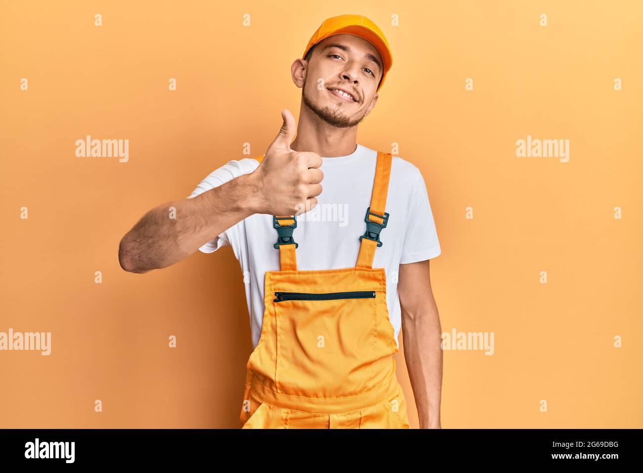 Hispanic young man wearing handyman uniform doing happy thumbs up ...