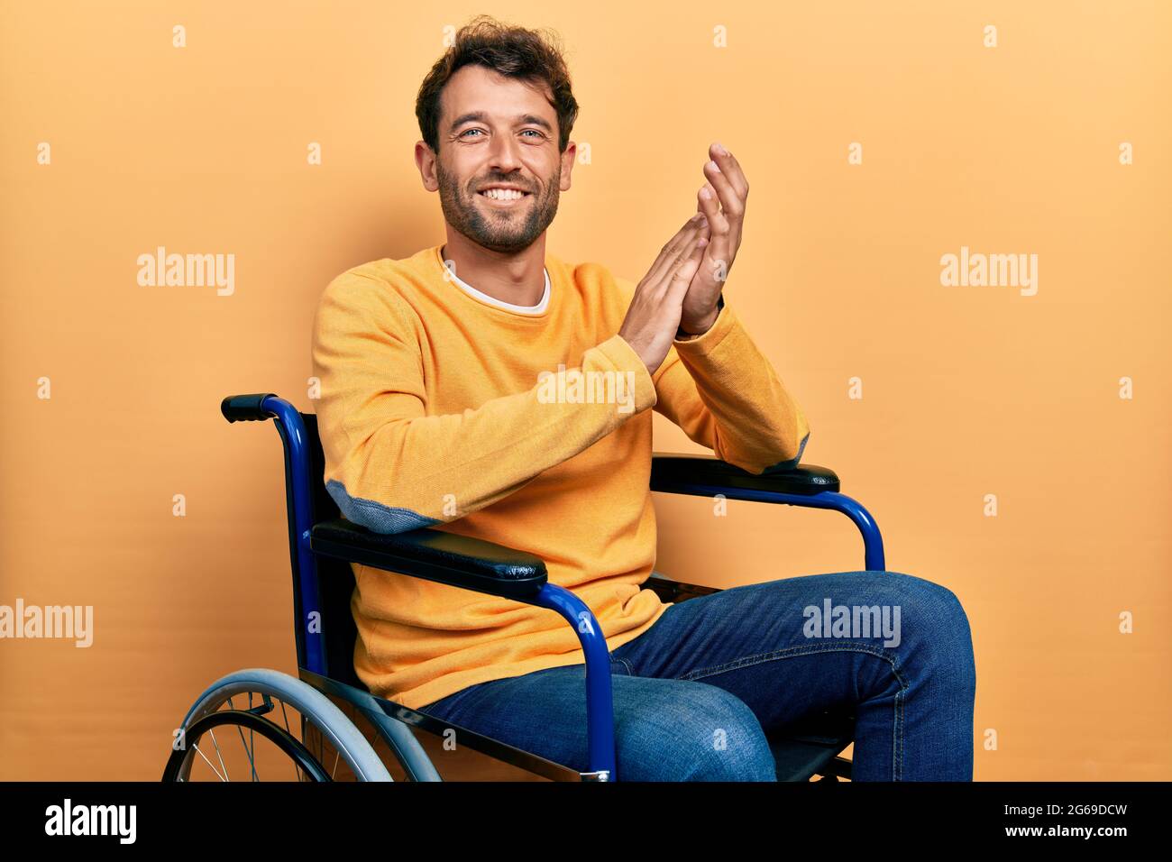 Handsome man with beard sitting on wheelchair clapping and applauding ...