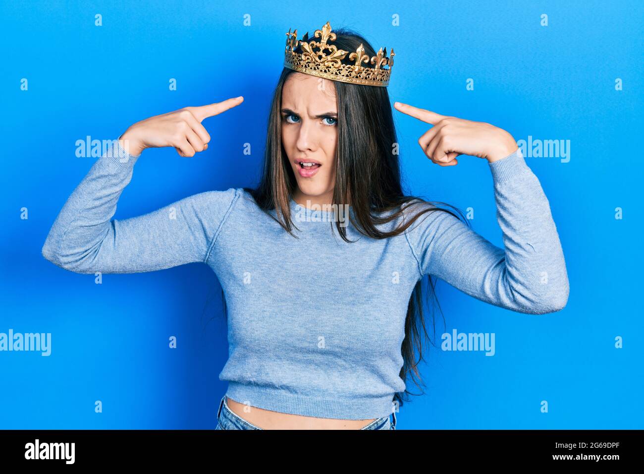 Young brunette teenager wearing princess crown clueless and confused ...