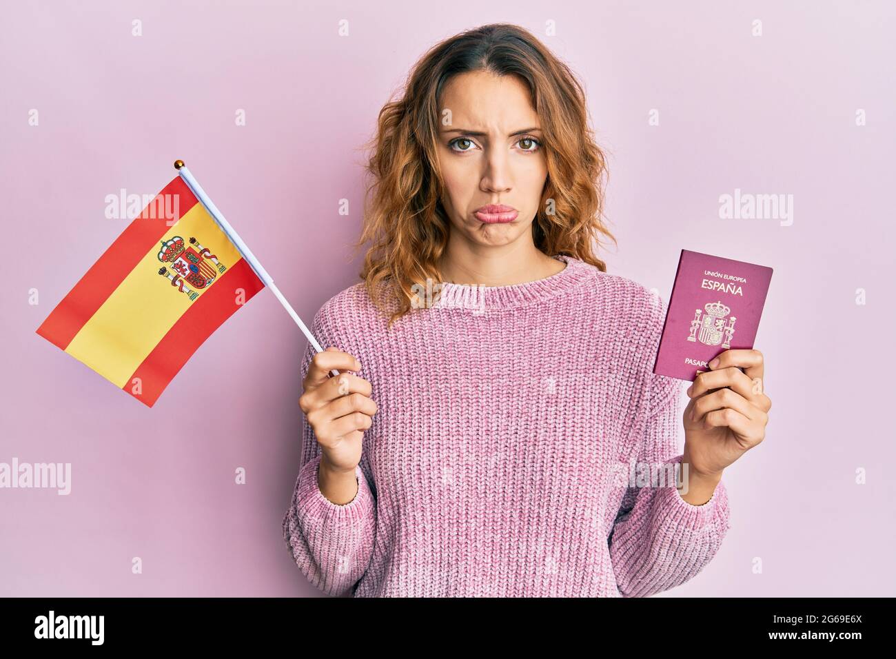 Young caucasian woman holding spain flag and passport depressed and ...