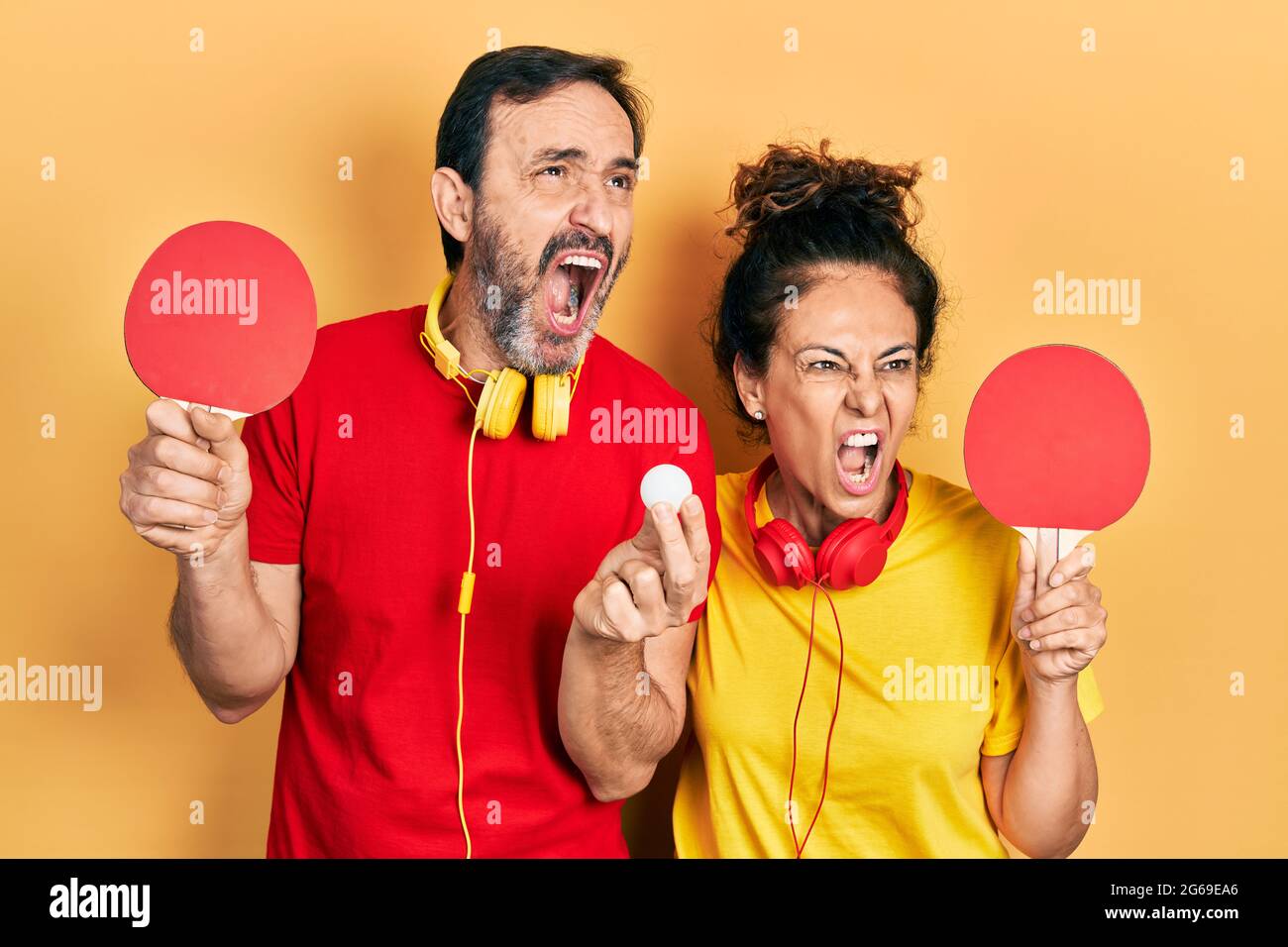 Middle age couple of hispanic woman and man holding red ping pong ...