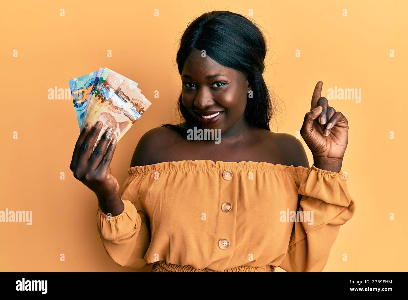 African young woman holding canadian dollars smiling with an idea or ...