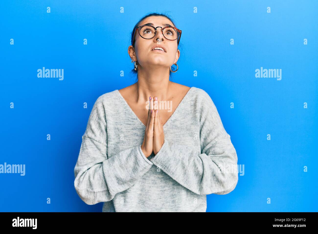 Young hispanic woman wearing casual clothes begging and praying with ...