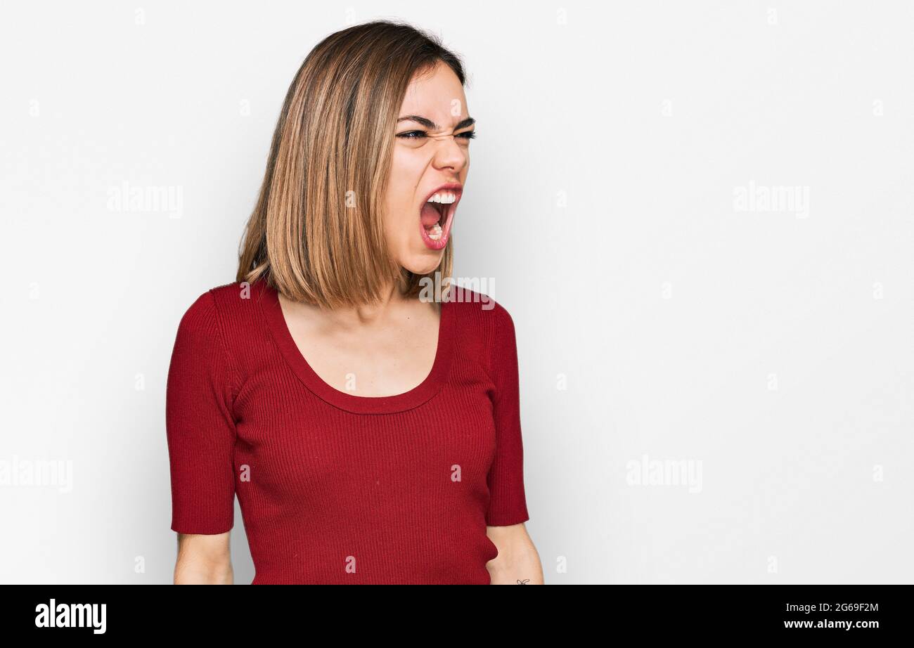 Young blonde girl wearing casual clothes angry and mad screaming ...