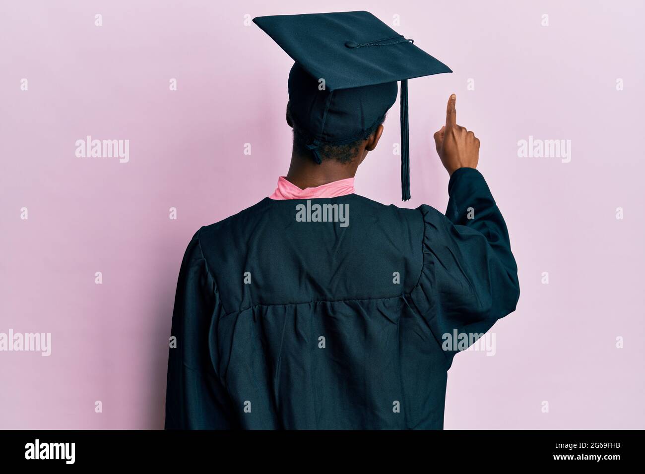Young african american girl wearing graduation cap and ceremony robe ...