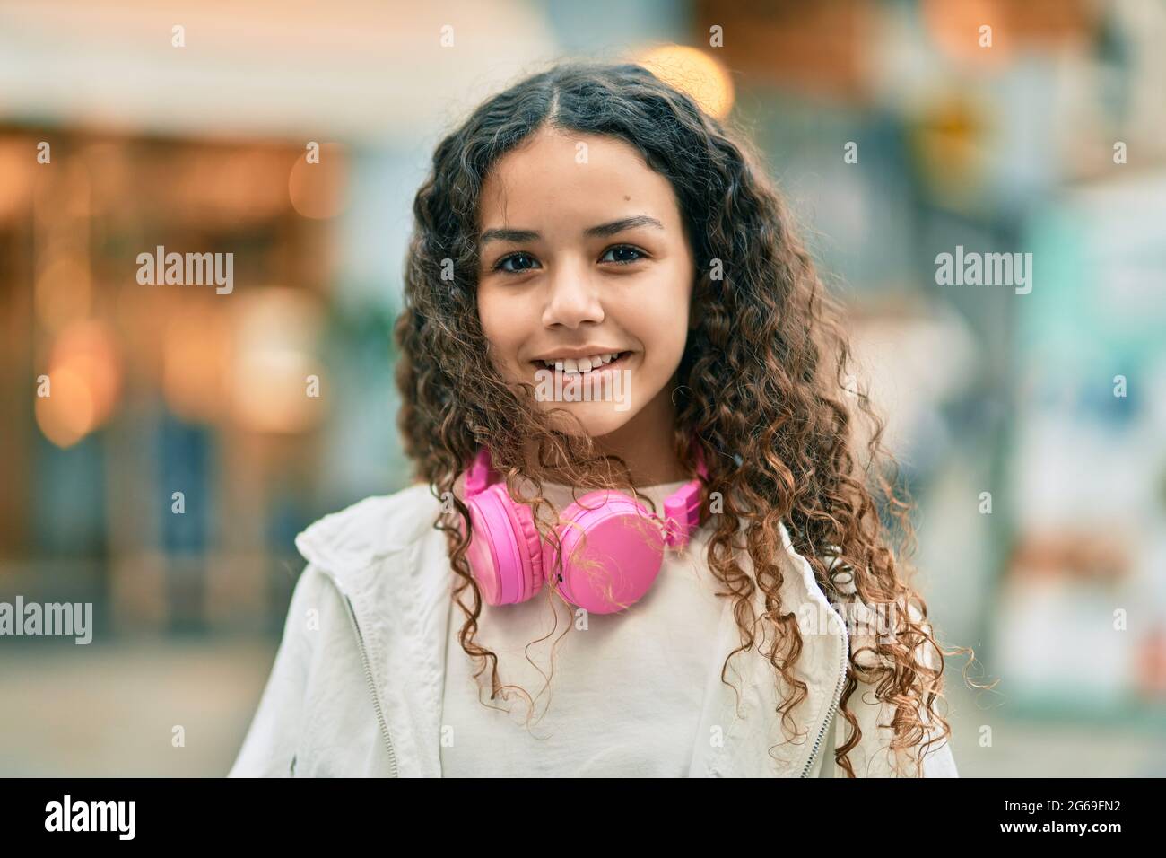 Hispanic child girl smiling happy using headphones at the city Stock ...