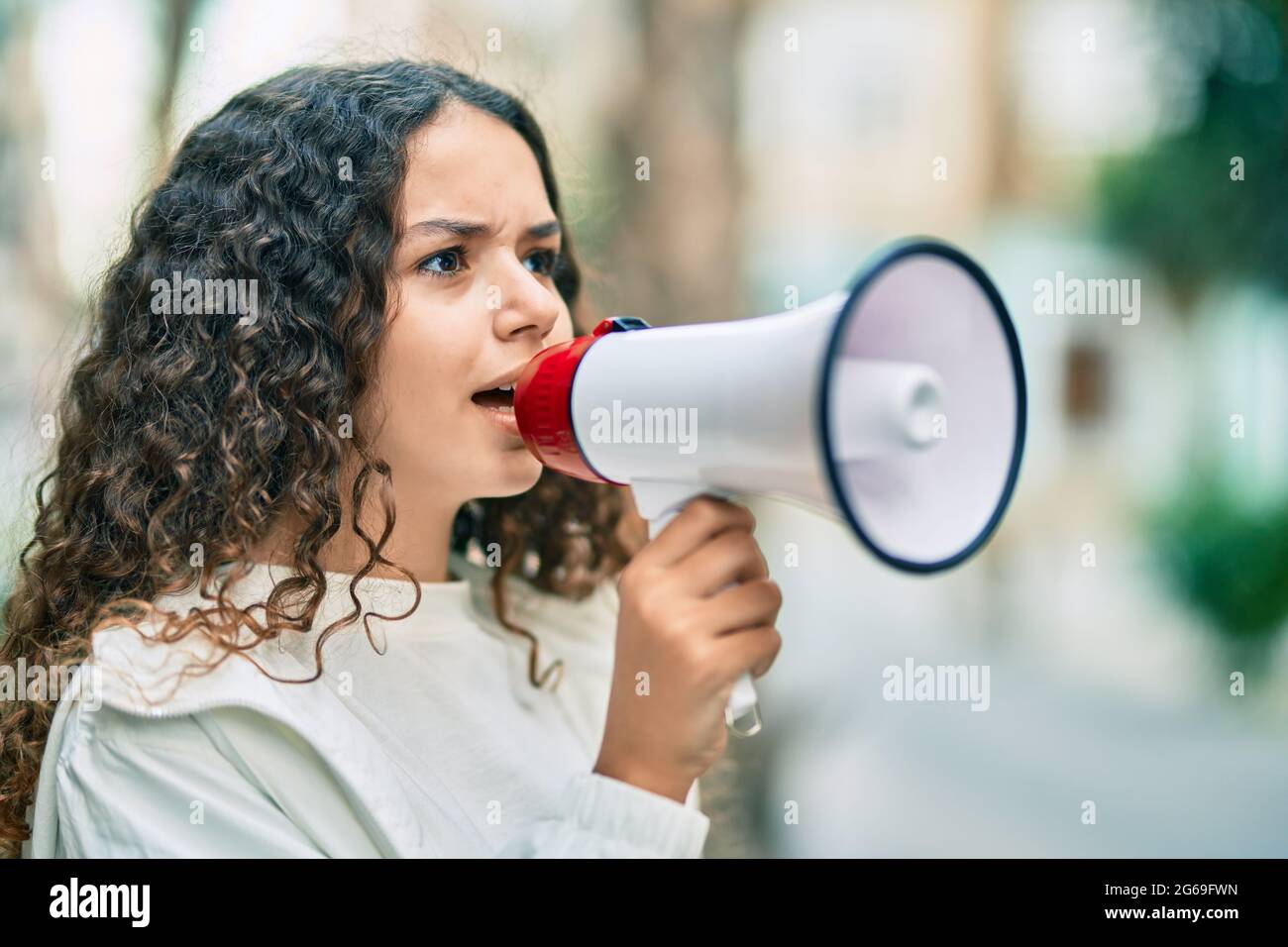 Hispanic child girl shouting angry using megaphone at the city Stock ...