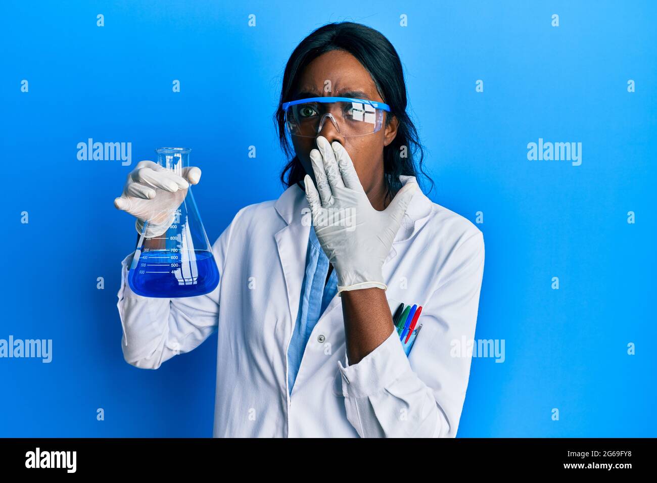 Young african american woman wearing scientist uniform holding test ...