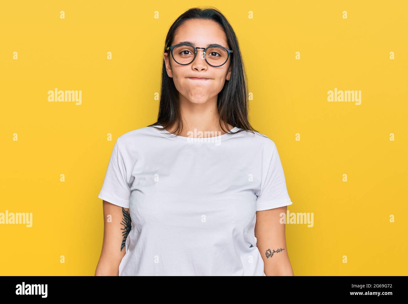 Young hispanic woman wearing casual white t shirt puffing cheeks with ...