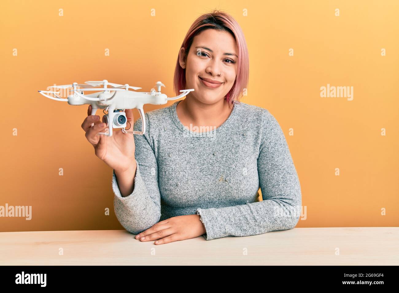 Hispanic woman with pink hair using drone looking positive and happy ...