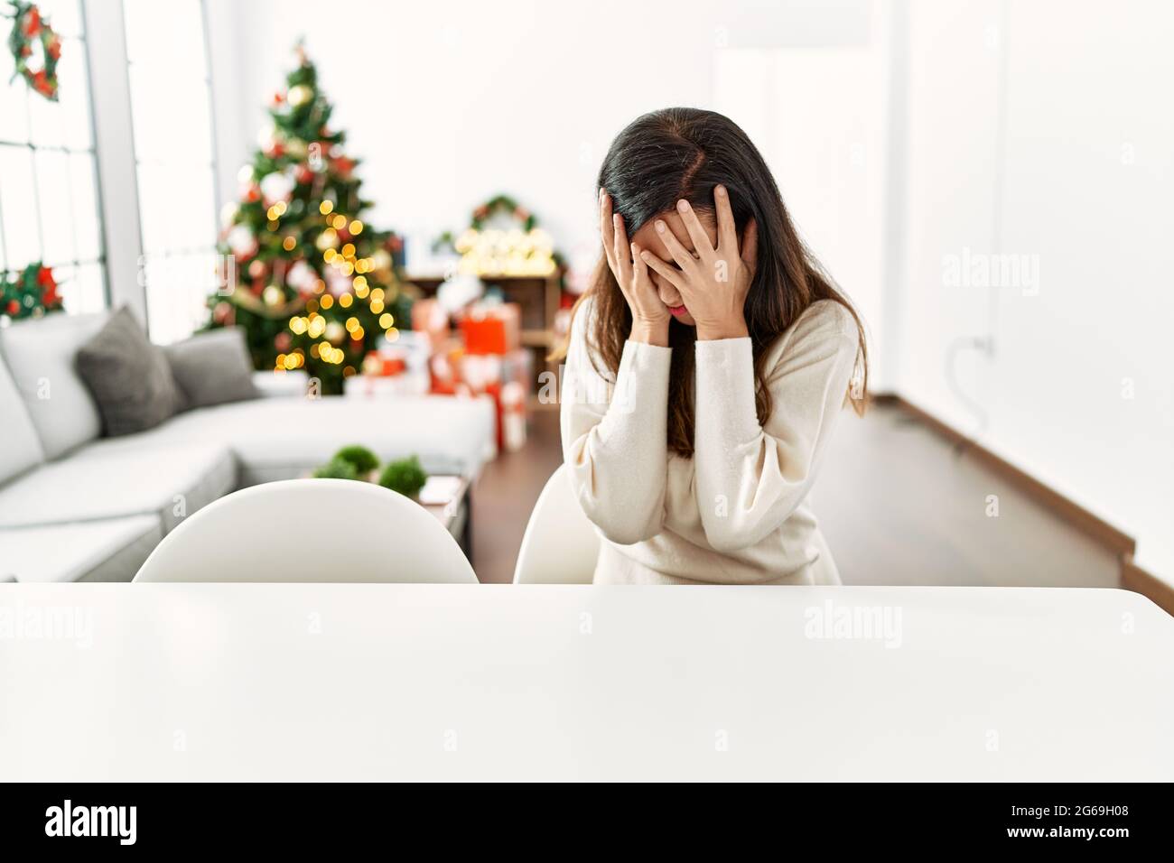 Beautiful caucasian woman sitting on the table by christmas tree with ...