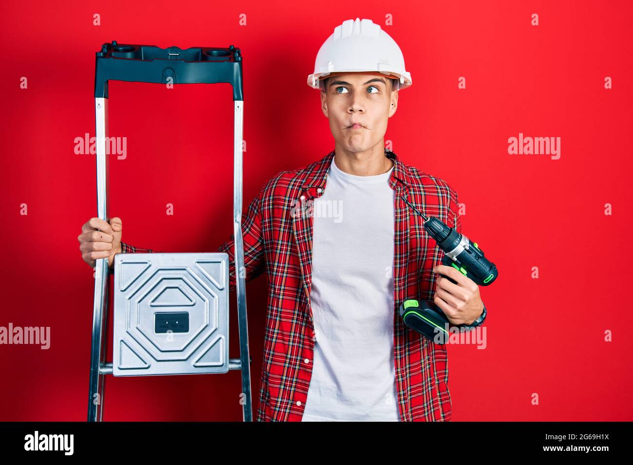 Young hispanic man holding screwdriver wearing hardhat by construction ...