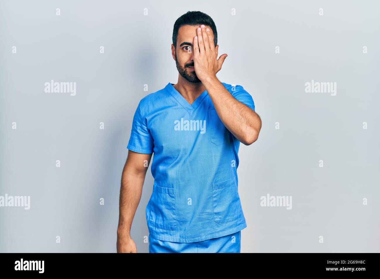 Handsome hispanic man with beard wearing blue male nurse uniform ...