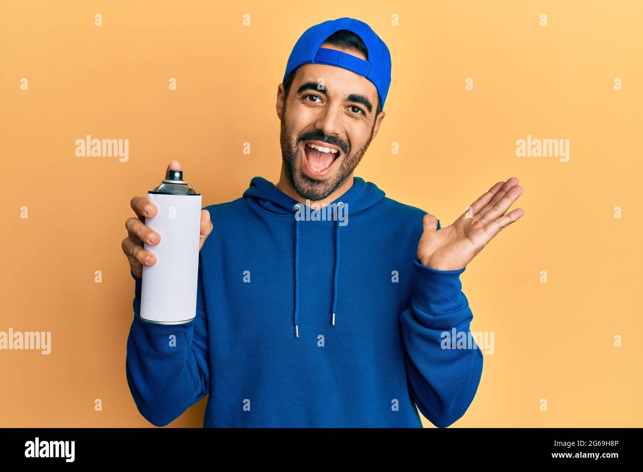 Young hispanic man wearing sweatshirt holding graffiti spray ...