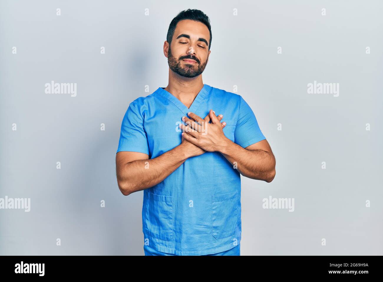 Handsome hispanic man with beard wearing blue male nurse uniform ...