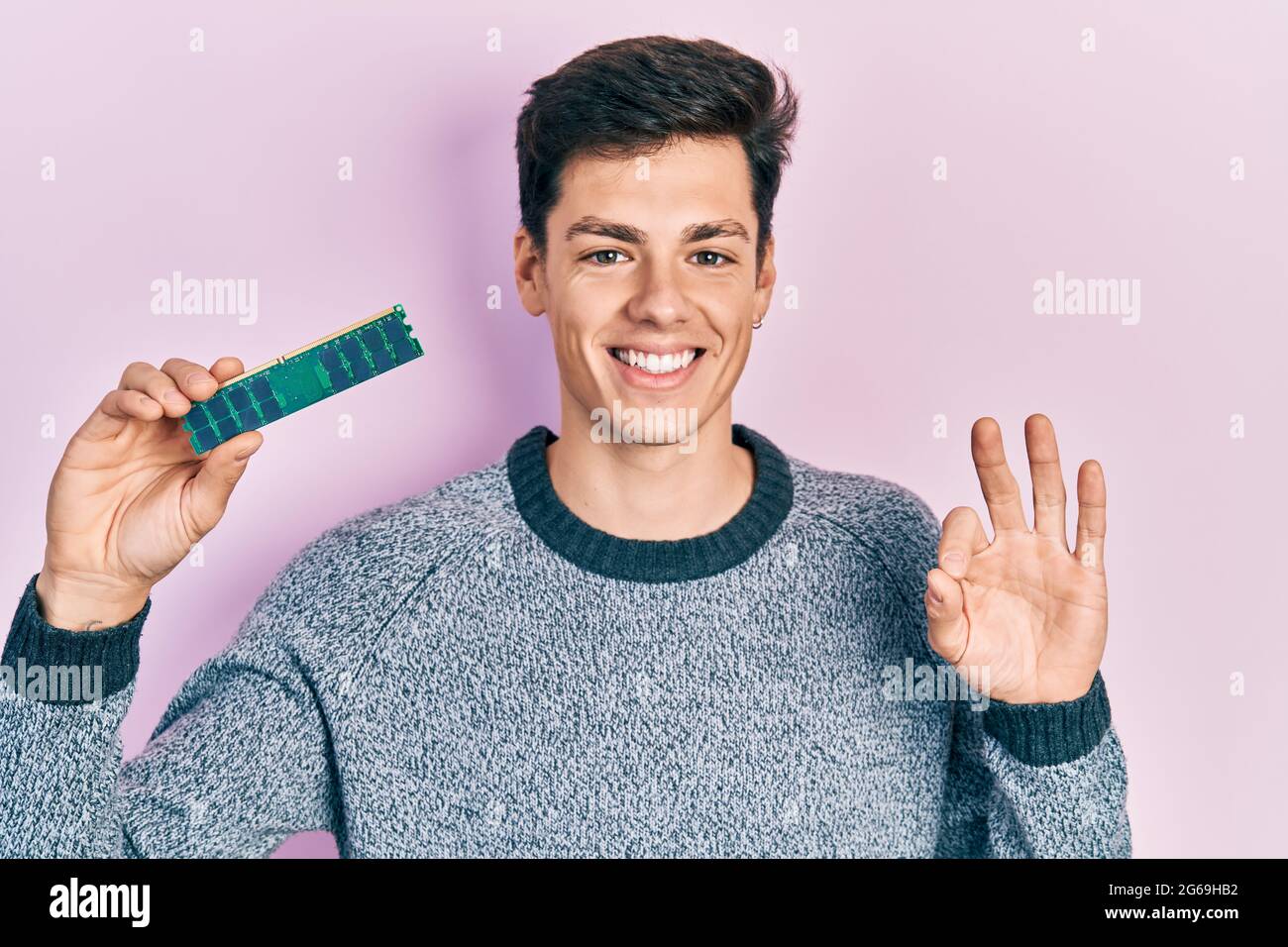 Young hispanic man holding memory ram doing ok sign with fingers ...