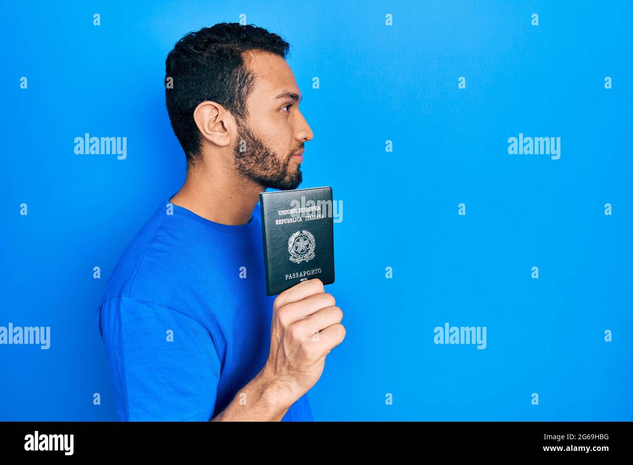 Hispanic man with beard holding italy passport looking to side, relax ...