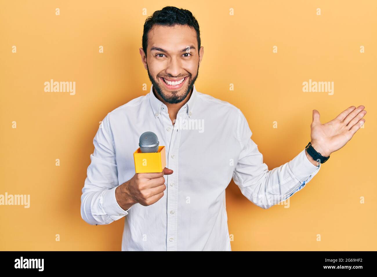 Hispanic man with beard holding reporter microphone celebrating victory ...