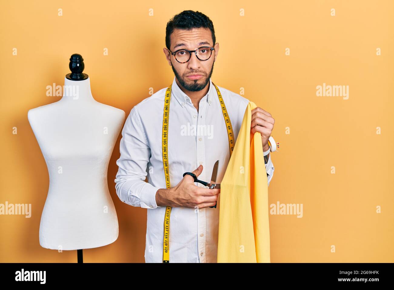 Hispanic man with beard dressmaker designer holding scissors and cloth ...