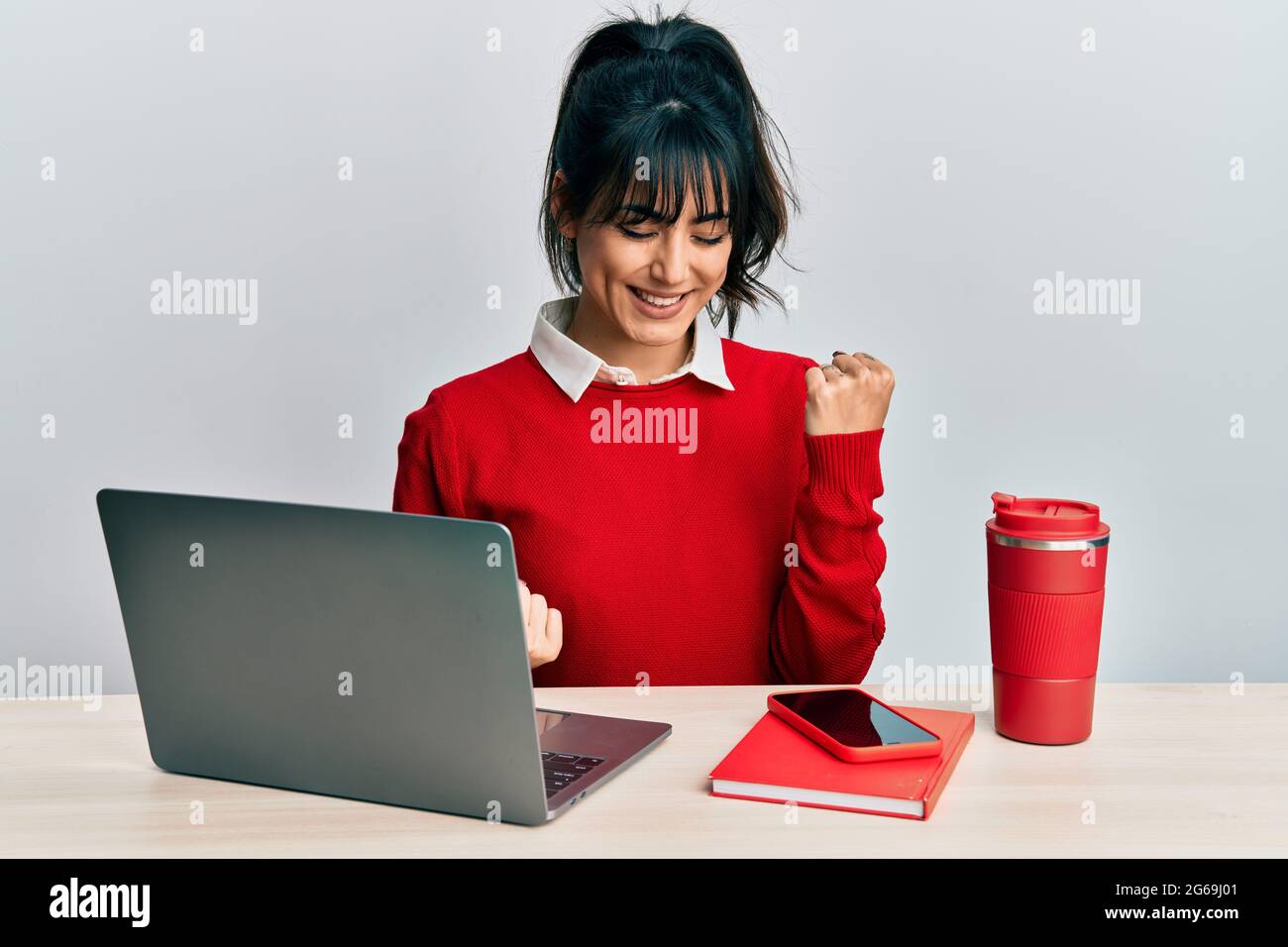 Young brunette woman with bangs working at the office with laptop ...