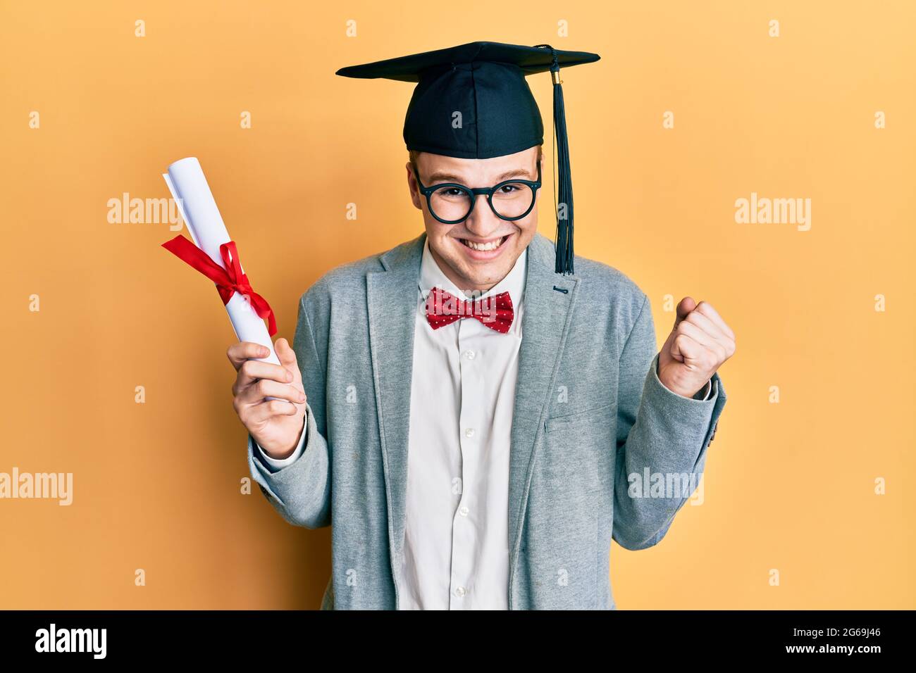 Young caucasian nerd man wearing glasses and graduation cap and holding ...