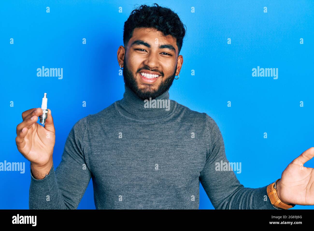 Arab man with beard holding spark plug celebrating achievement with ...
