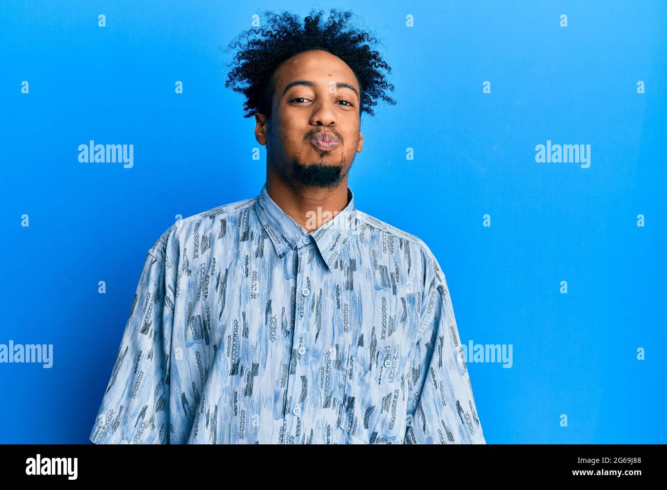 Young african american man with beard wearing casual clothes puffing ...