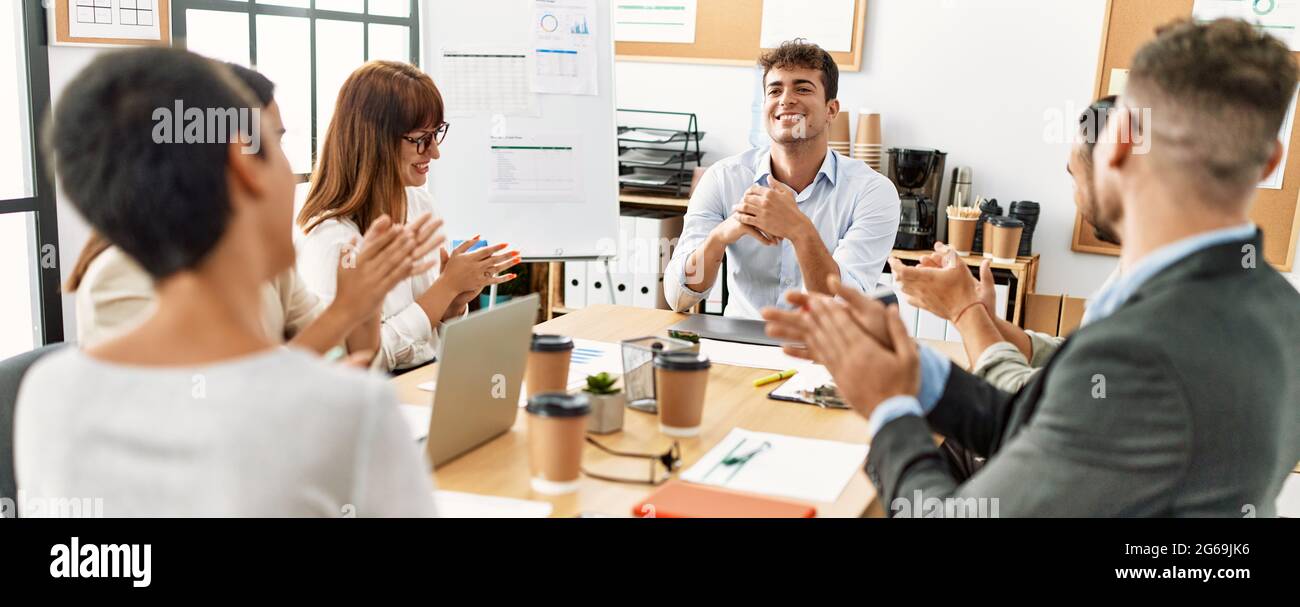 Group of business workers smiling and clapping to partner at the office ...