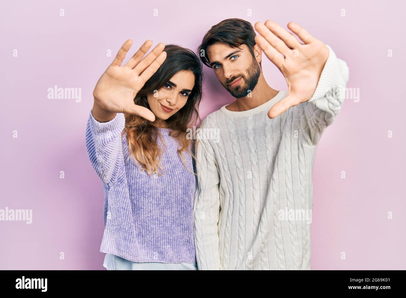 Young Hispanic Couple Wearing Casual Clothes Doing Frame Using Hands