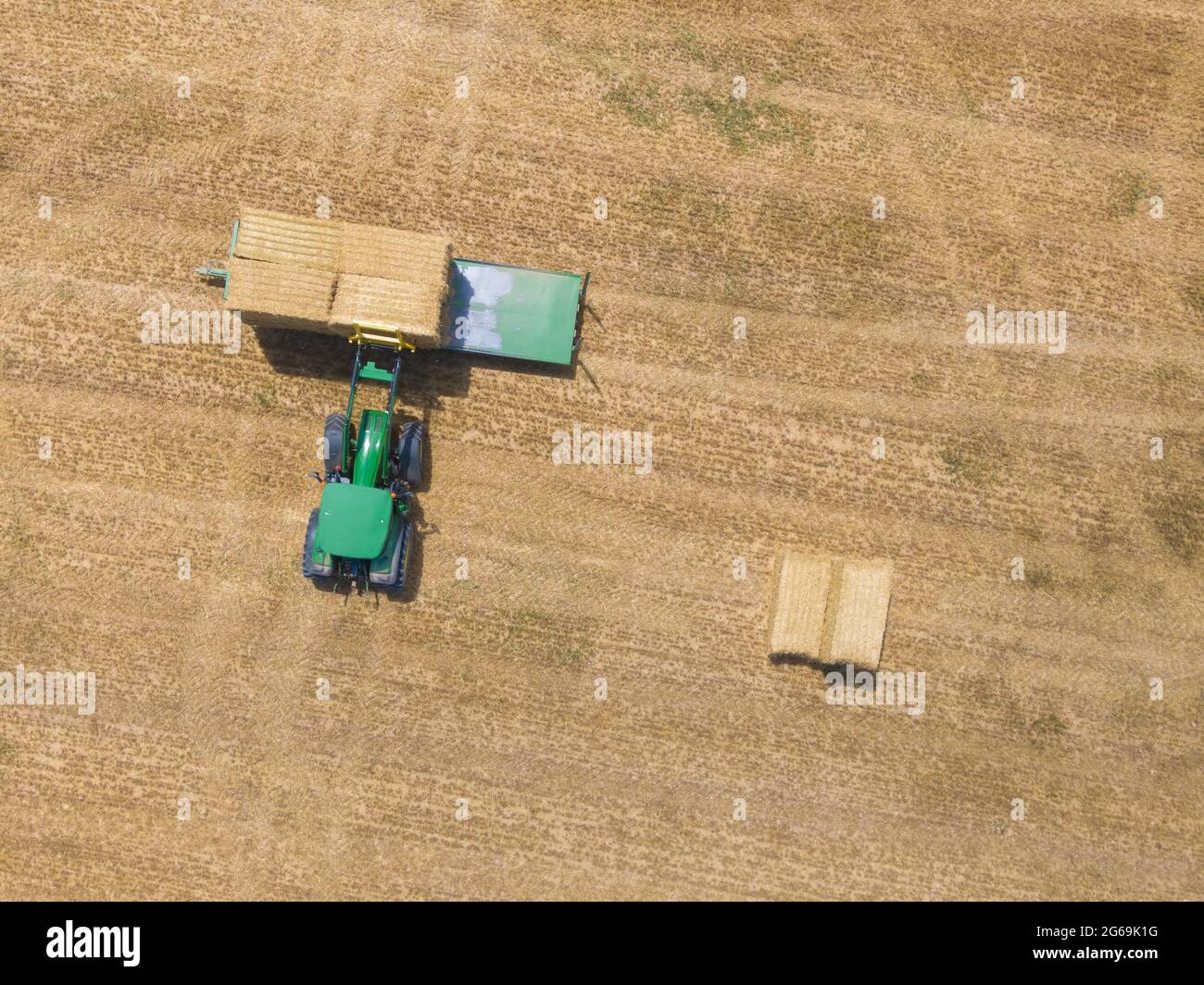 Top view of green tractor loading straw bales on a trailer, photo taken ...