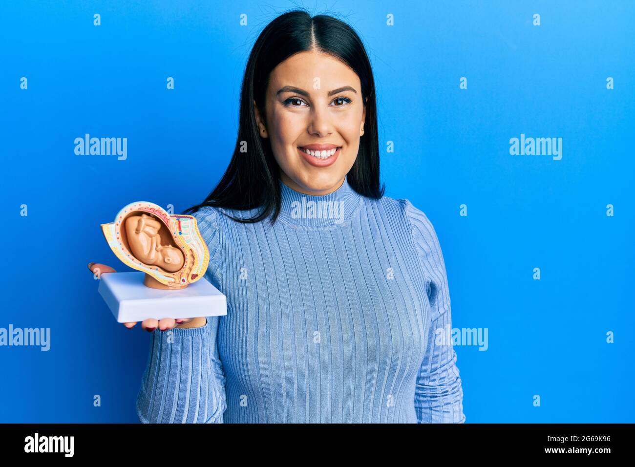 Beautiful brunette woman holding anatomical model of female uterus with ...