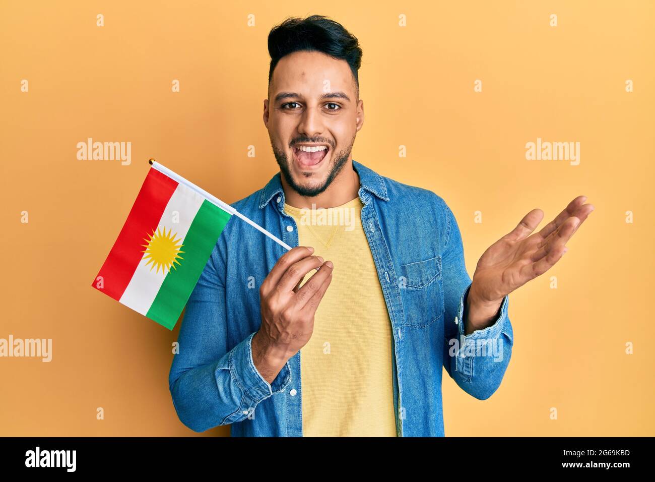 Young arab man holding kurdistan flag celebrating achievement with ...