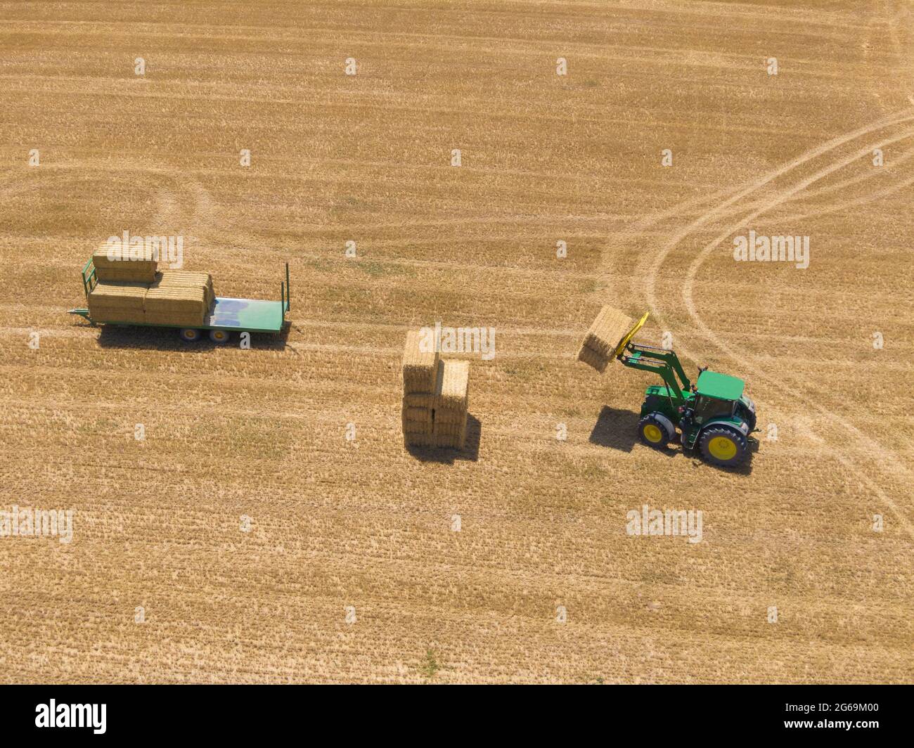 Top view of green tractor loading straw bales on a trailer, photo taken ...