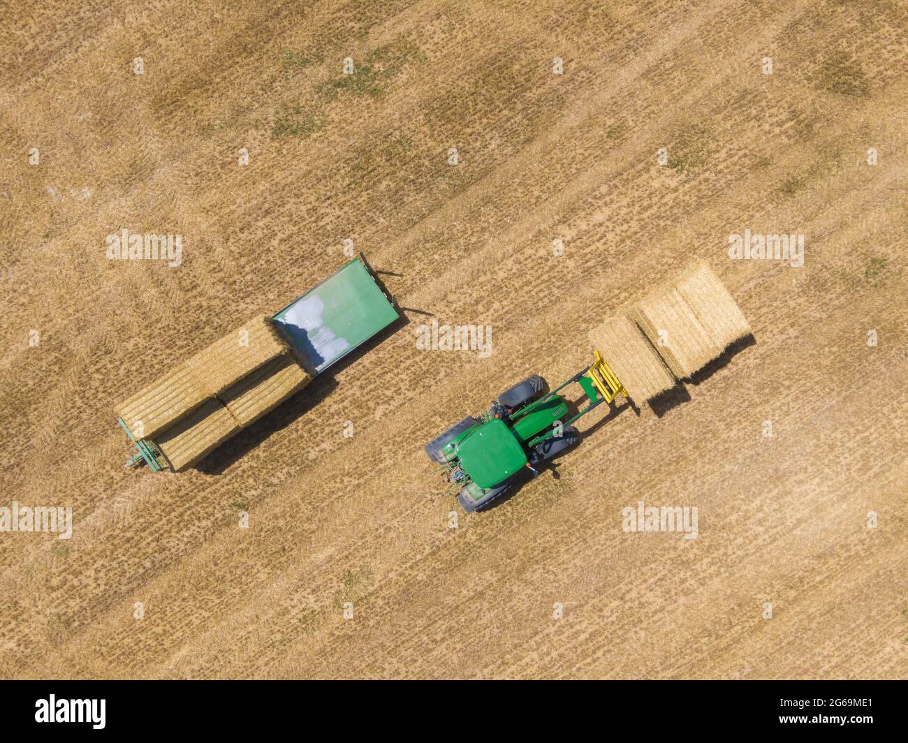 Top view of green tractor loading straw bales on a trailer, photo taken ...