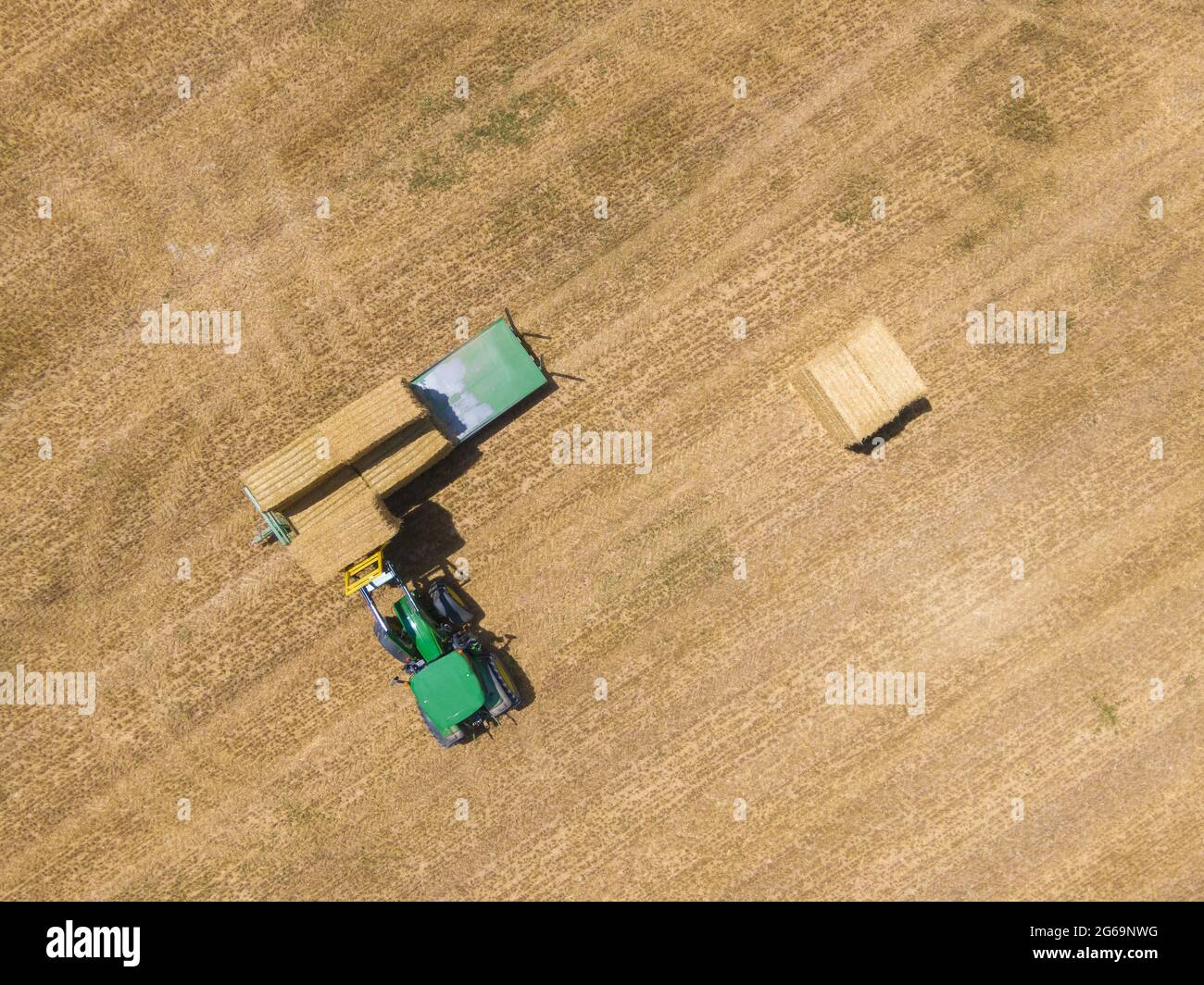 Top view of green tractor loading straw bales on a trailer, photo taken ...