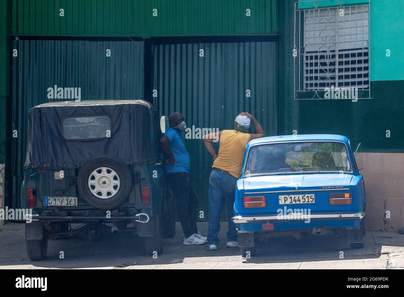Two drivers talking close to their cars and the city smog. To the left ...