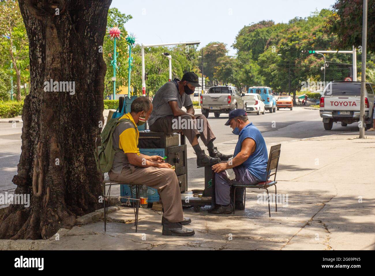 Cuban man working as a shoeshiner on a city sidewalk in Santiago de ...