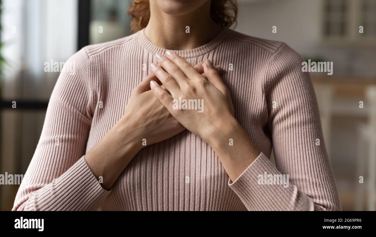Young woman holding folded hands on chest heart Stock Photo - Alamy