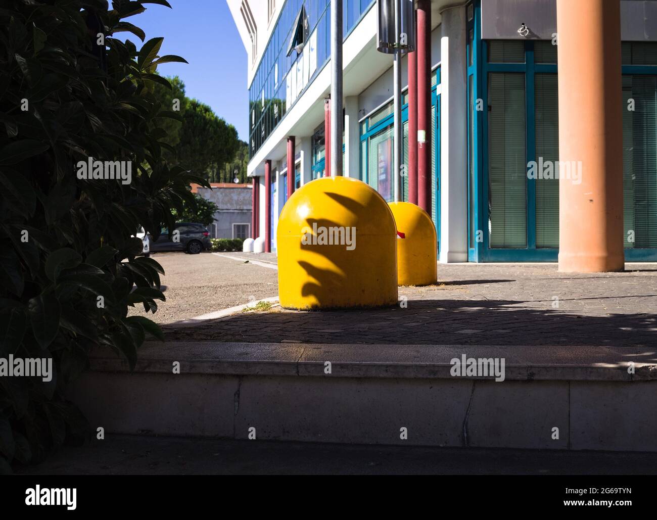 Two yellow colored concrete traffic bollards on the pavement (Marche ...