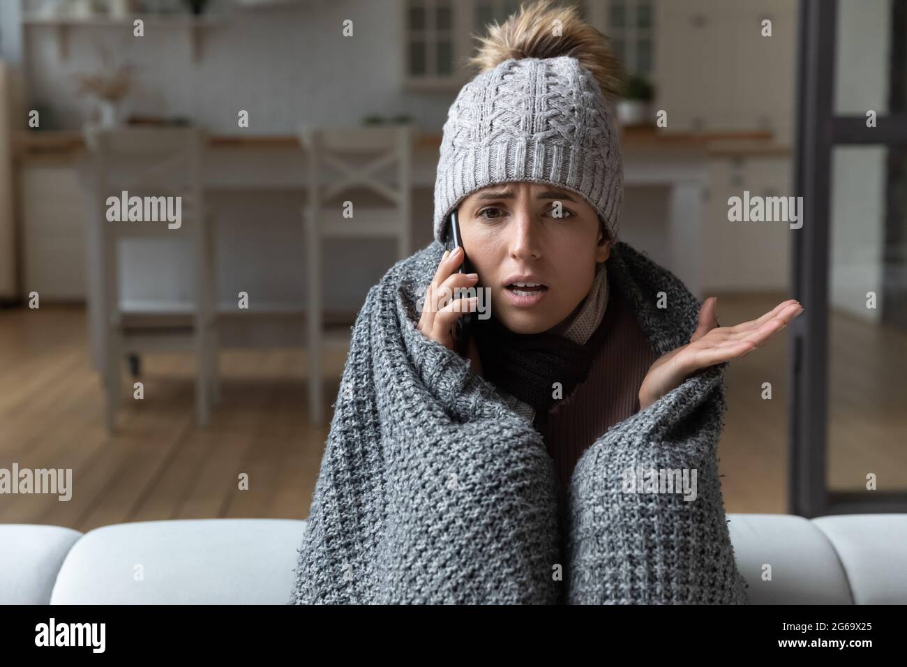 Unhappy young woman in warm plaid holding telephone call Stock Photo ...